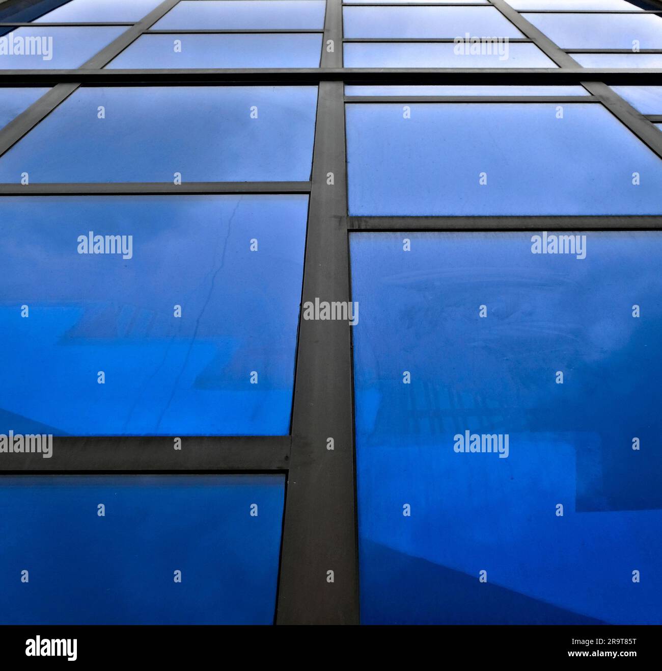 Blue opalescent neon glass and dark window frames, detail of modern ...