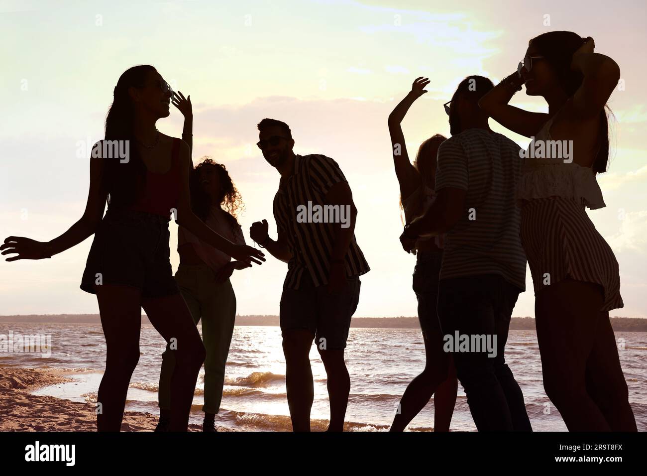 Friends dancing on sandy beach during summer party. Silhouettes of ...