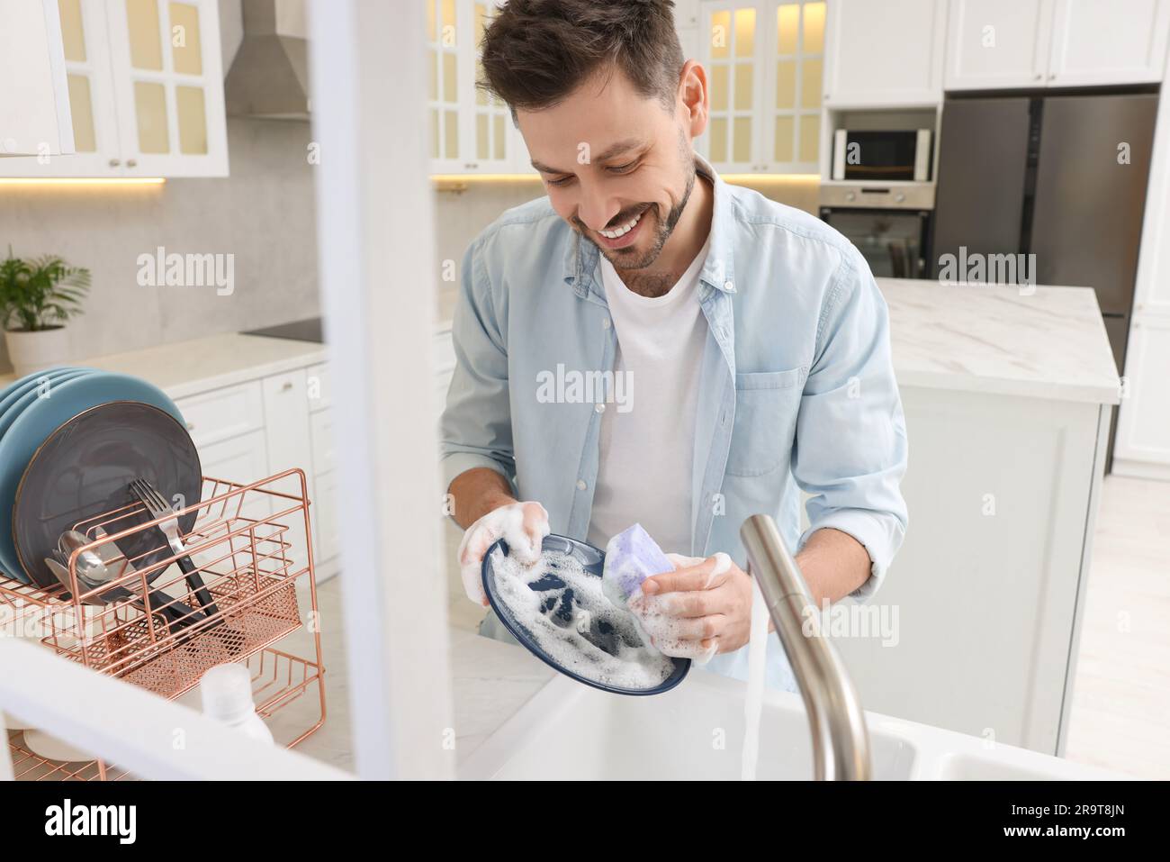 Man washing plate above sink in kitchen, view from outside Stock Photo ...