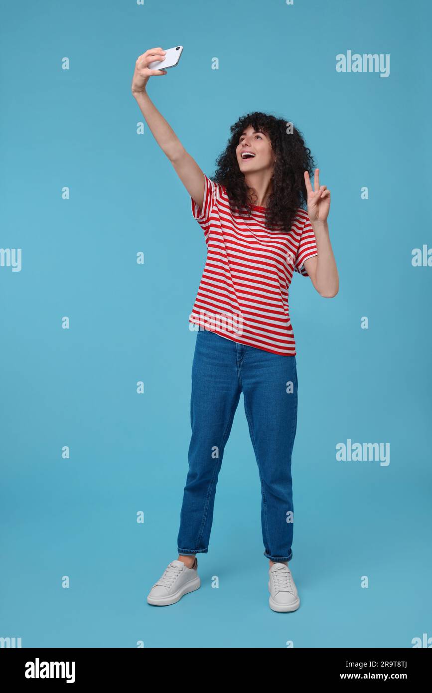 Beautiful young woman taking selfie on light blue background Stock ...