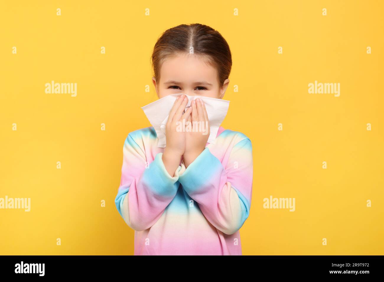 Girl blowing nose in tissue on orange background. Cold symptoms Stock ...