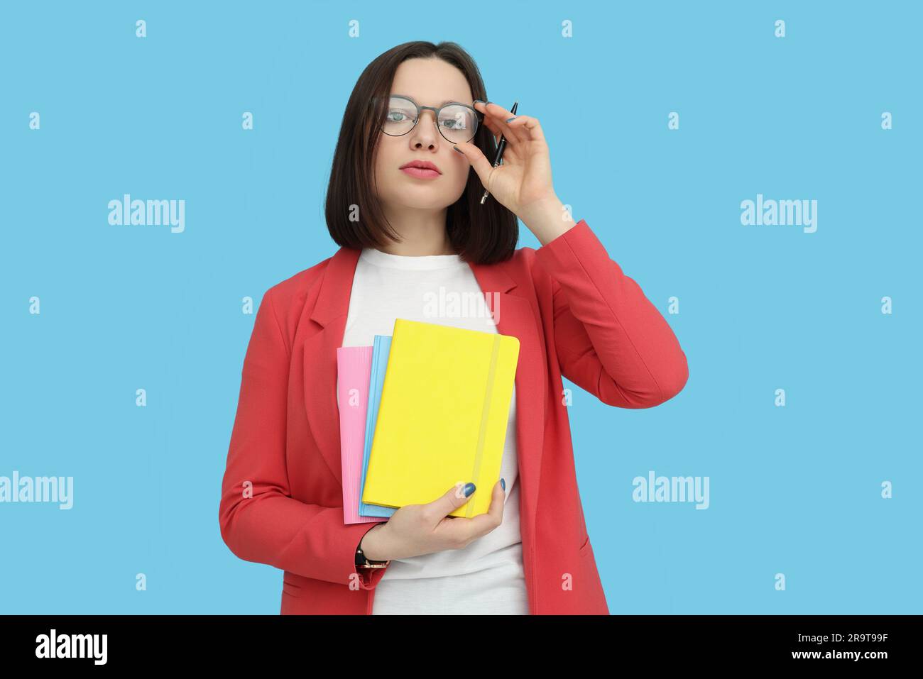 Young intern with notebooks and pen on light blue background Stock ...