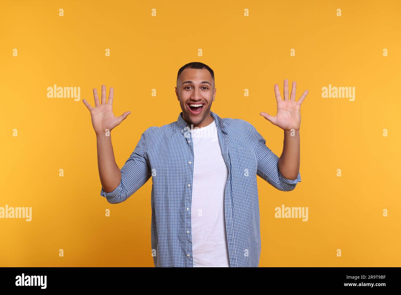 Man giving high five with both hands on yellow background Stock Photo ...
