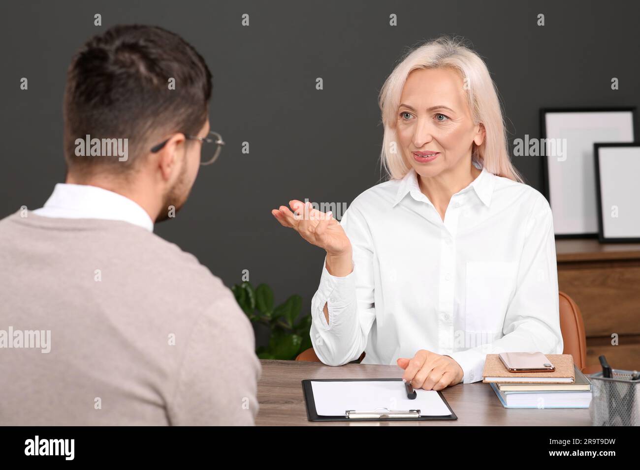 Woman having conversation with man at wooden table in office. Manager ...