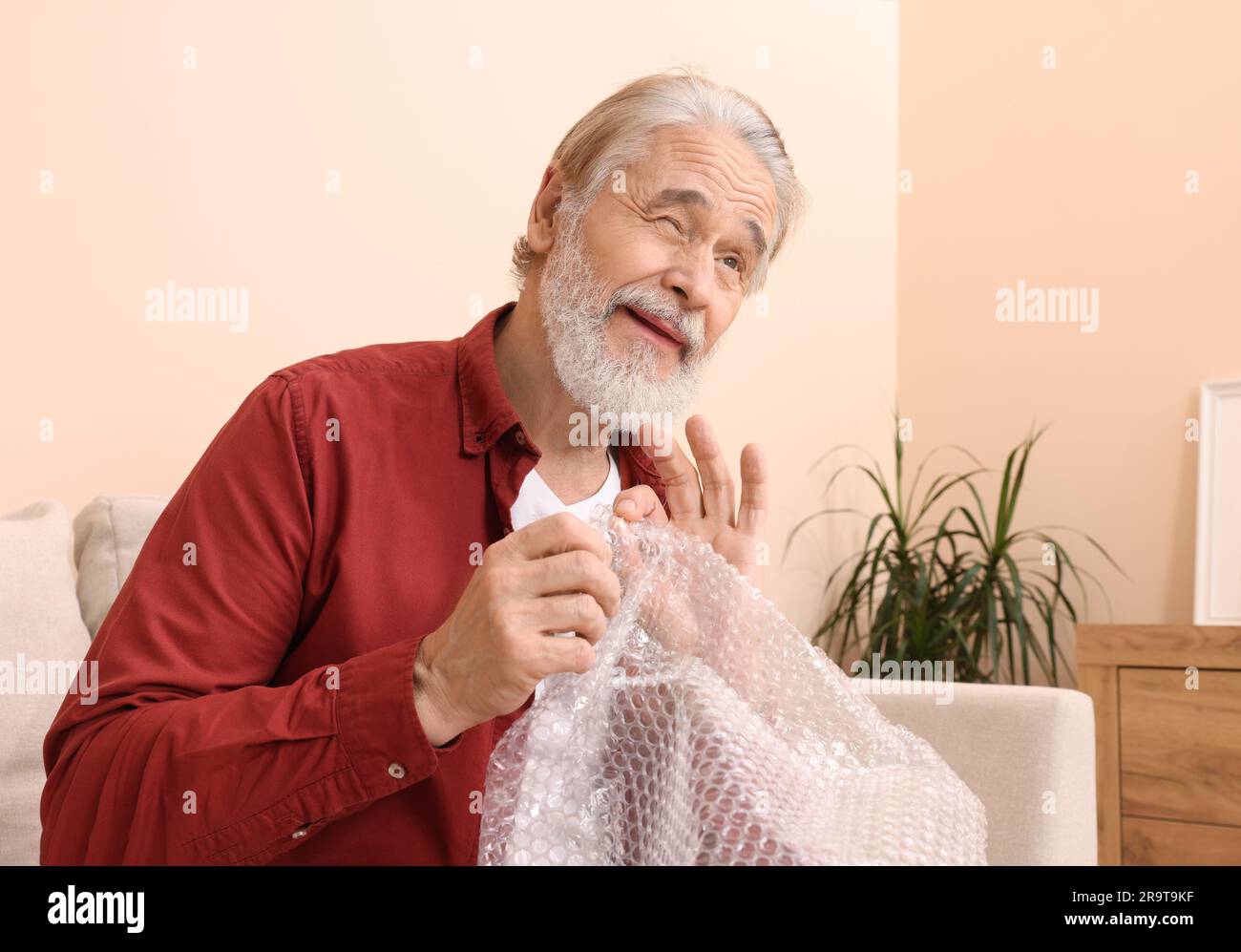 Emotional senior man popping bubble at home. Stress relief Stock Photo ...