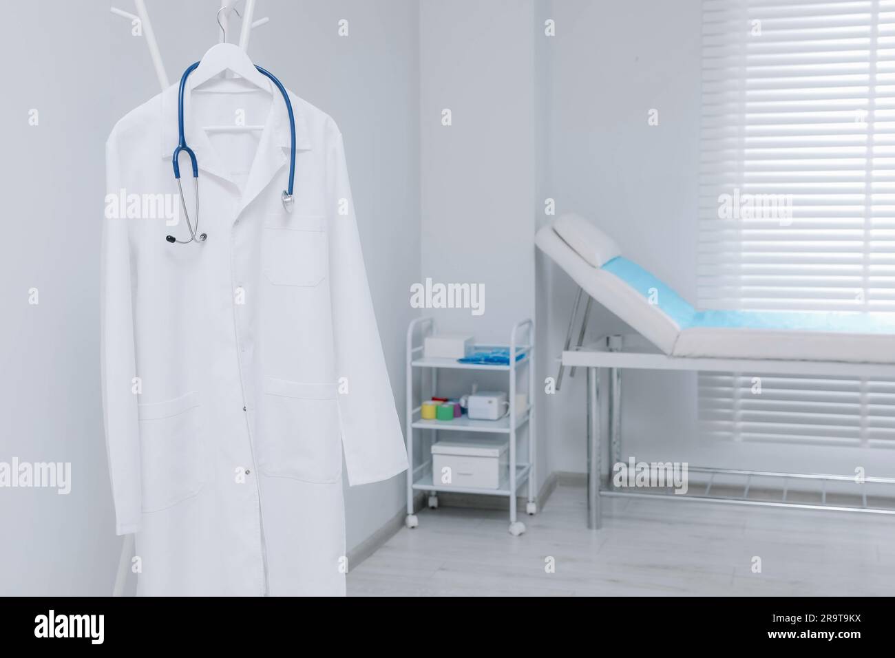 White doctor's gown and stethoscope hanging on rack in clinic. Space ...