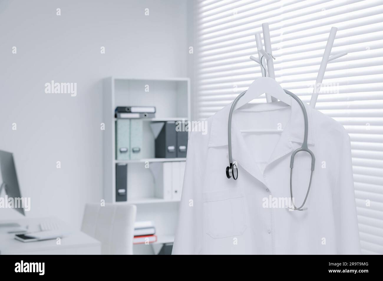 White doctor's gown and stethoscope hanging on rack in clinic, closeup ...