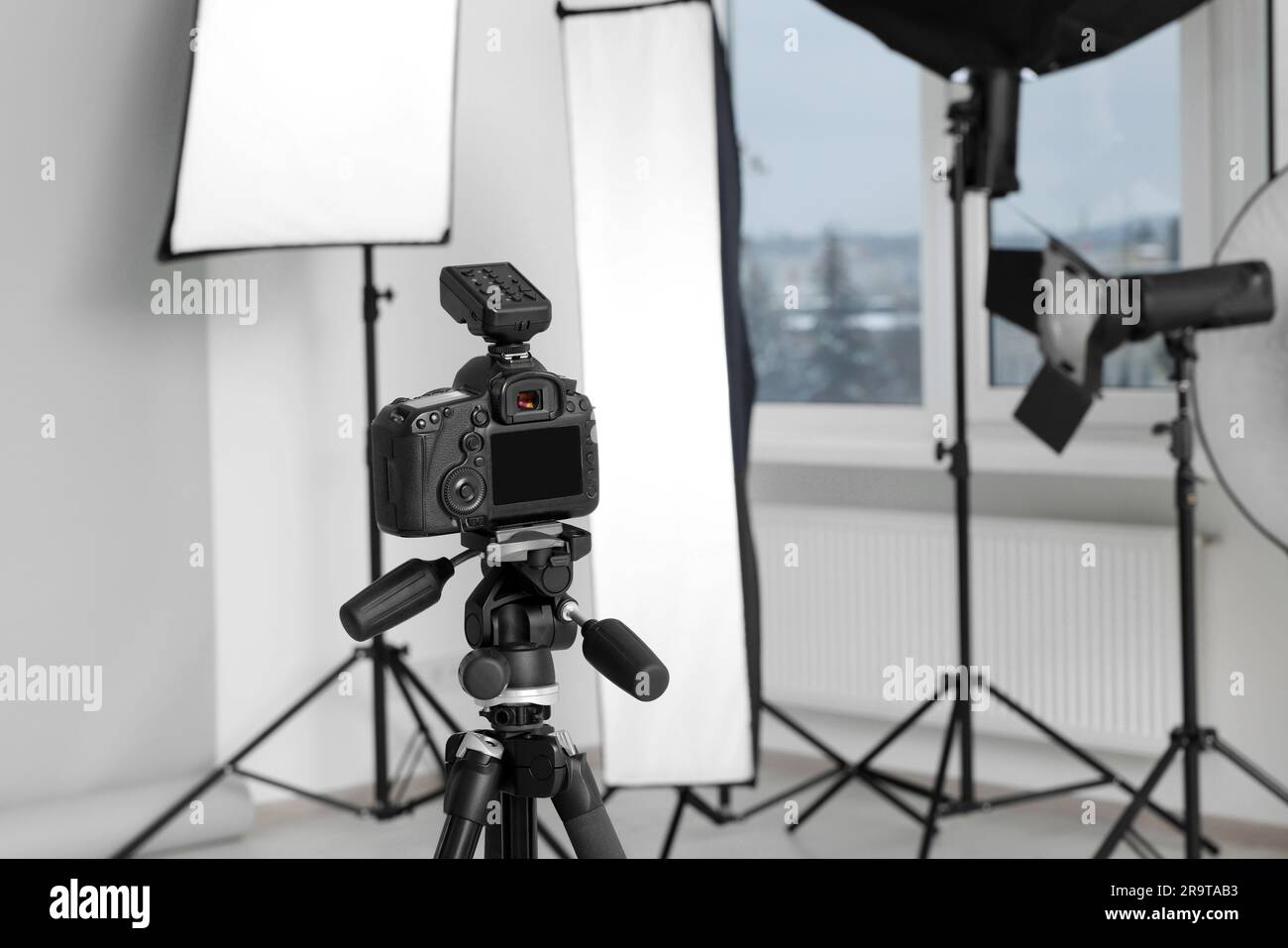 Camera on tripod and professional lighting equipment in modern photo ...