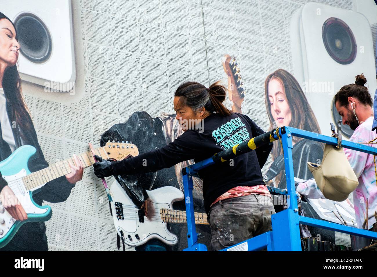 Artist works on a hand-drawn advertising mural of Fender guitarsi in ...