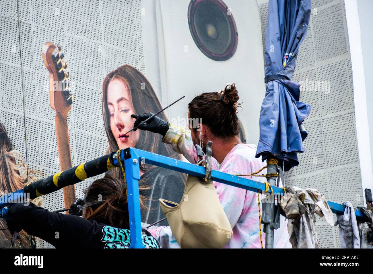Artist works on a hand-drawn advertising mural of Fender guitarsi in ...