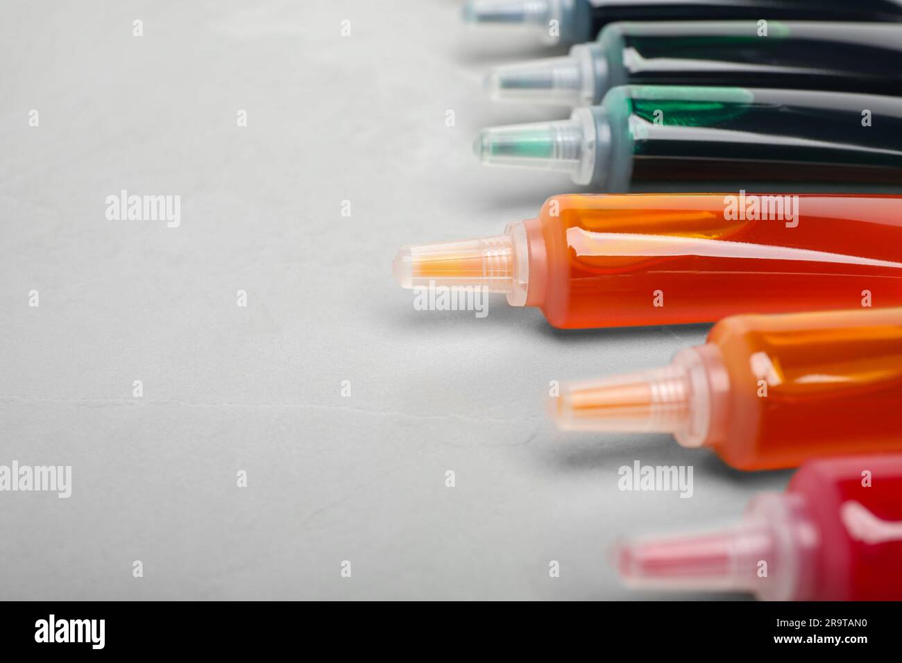 Tubes with different food coloring on white background, closeup. Space ...