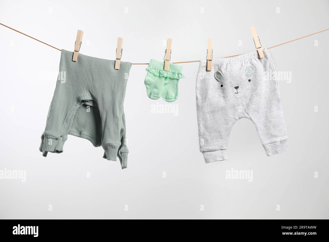 Cute baby clothes drying on washing line against white background Stock ...