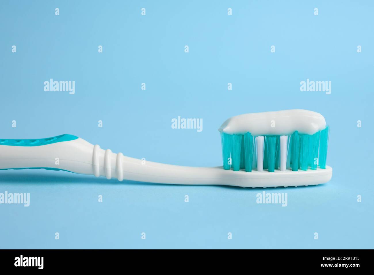Brush with toothpaste on light blue background, closeup Stock Photo - Alamy