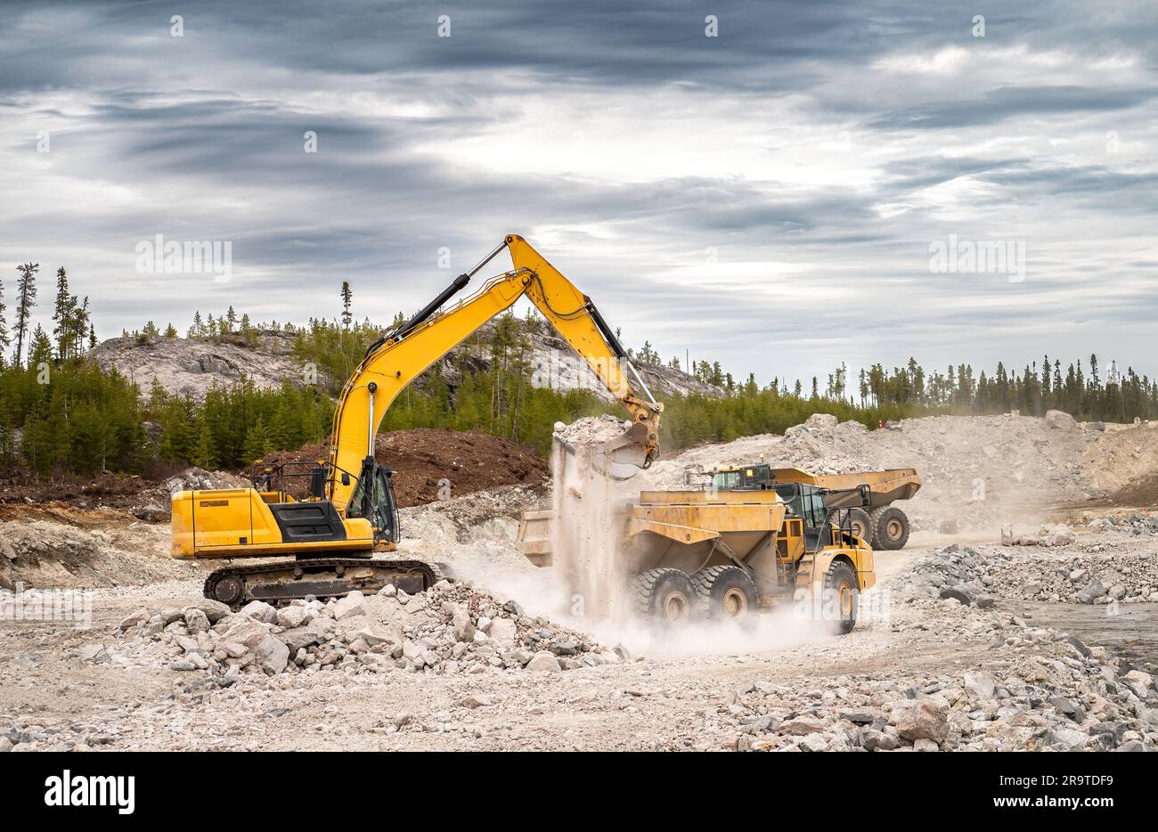 Excavator loading dumpers with blasted stone and causing a cloud of ...