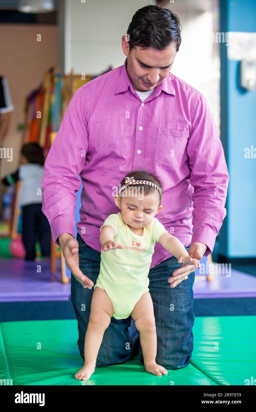 Young father teaching his ten months baby daughter to walk. Early ...
