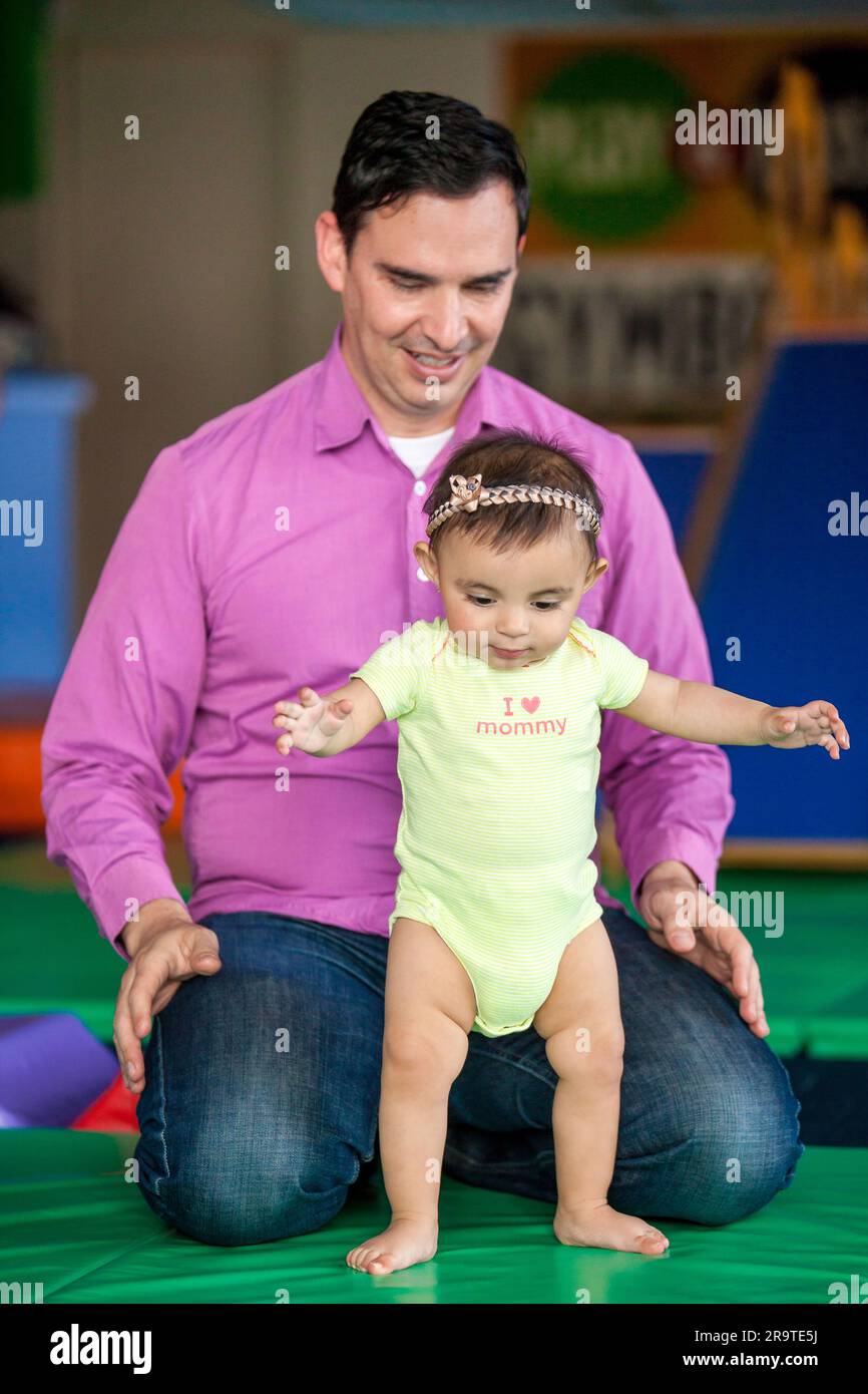 Beautiful ten months baby girl learning to walk helped by her father ...
