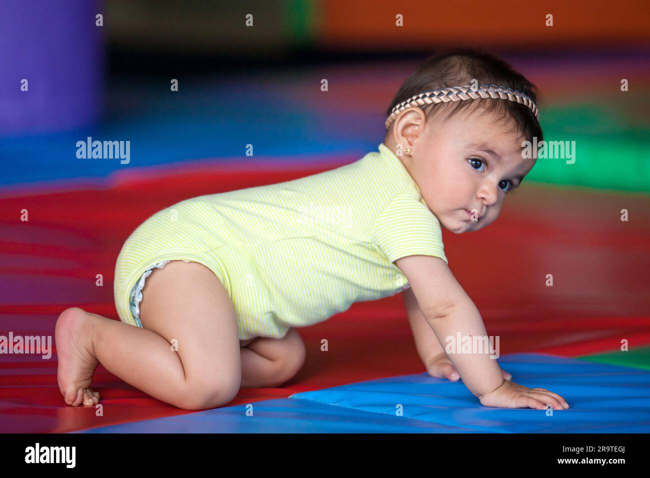 Beautiful ten months baby girl crawling on a colorful background. Early ...