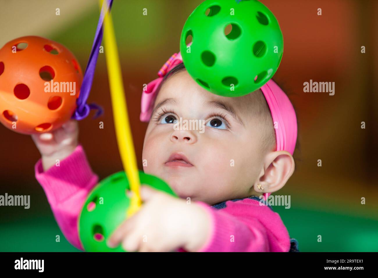 Beautiful ten months baby girl playing with colorful balls. Early ...