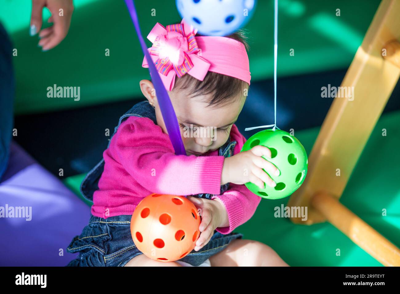 Beautiful ten months baby girl playing with colorful balls. Early ...