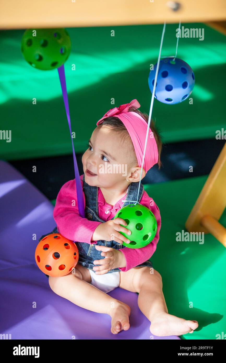 Beautiful ten months baby girl playing with colorful balls. Early ...