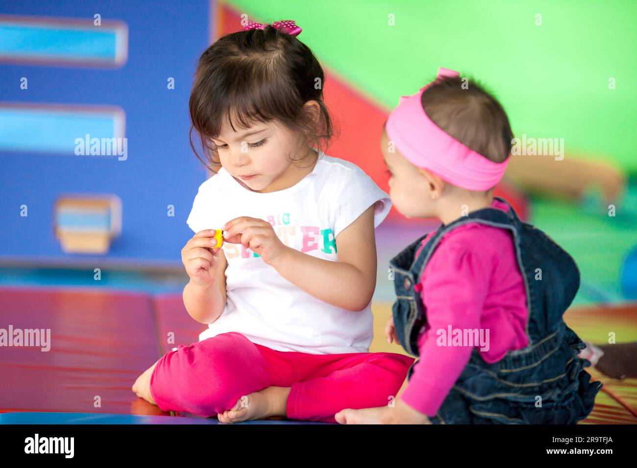 Beautiful small girl playing with her ten months baby girl sister ...