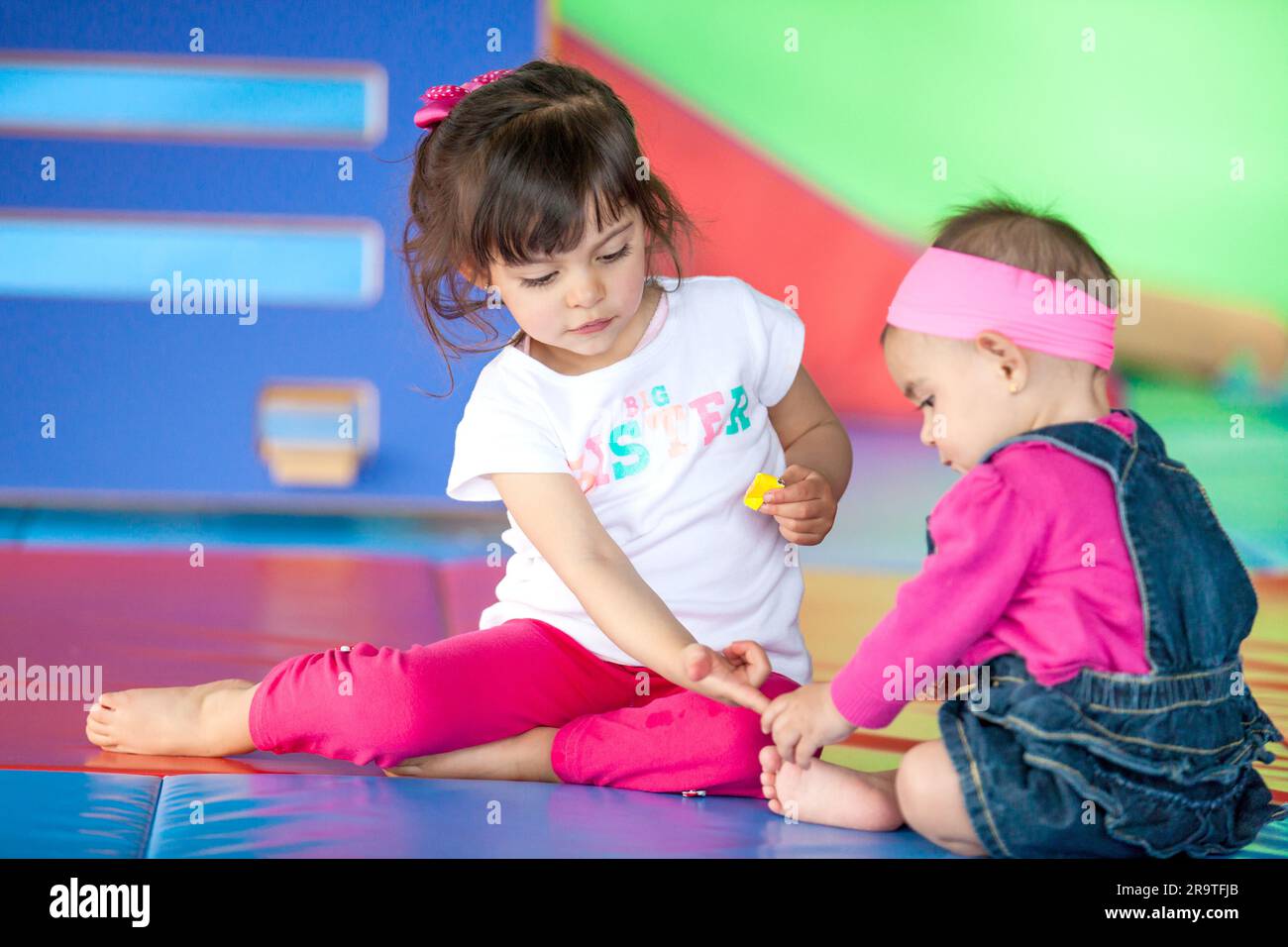 Beautiful small girl playing with her ten months baby girl sister ...