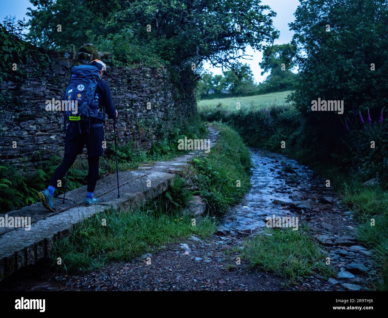 A hiker is seen walking during the sunrise on a stone pavement. The ...