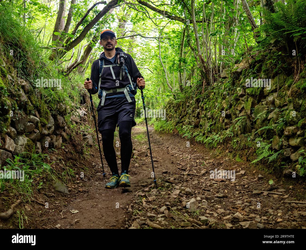 A pilgrim is seen climbing down with the help of walking sticks. The ...