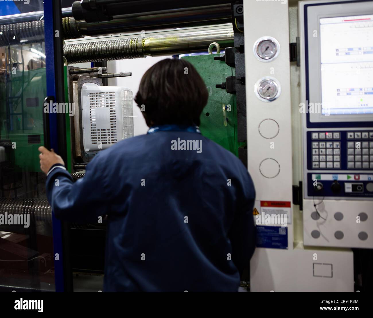 Industrial technician operate injection molding press machine ...