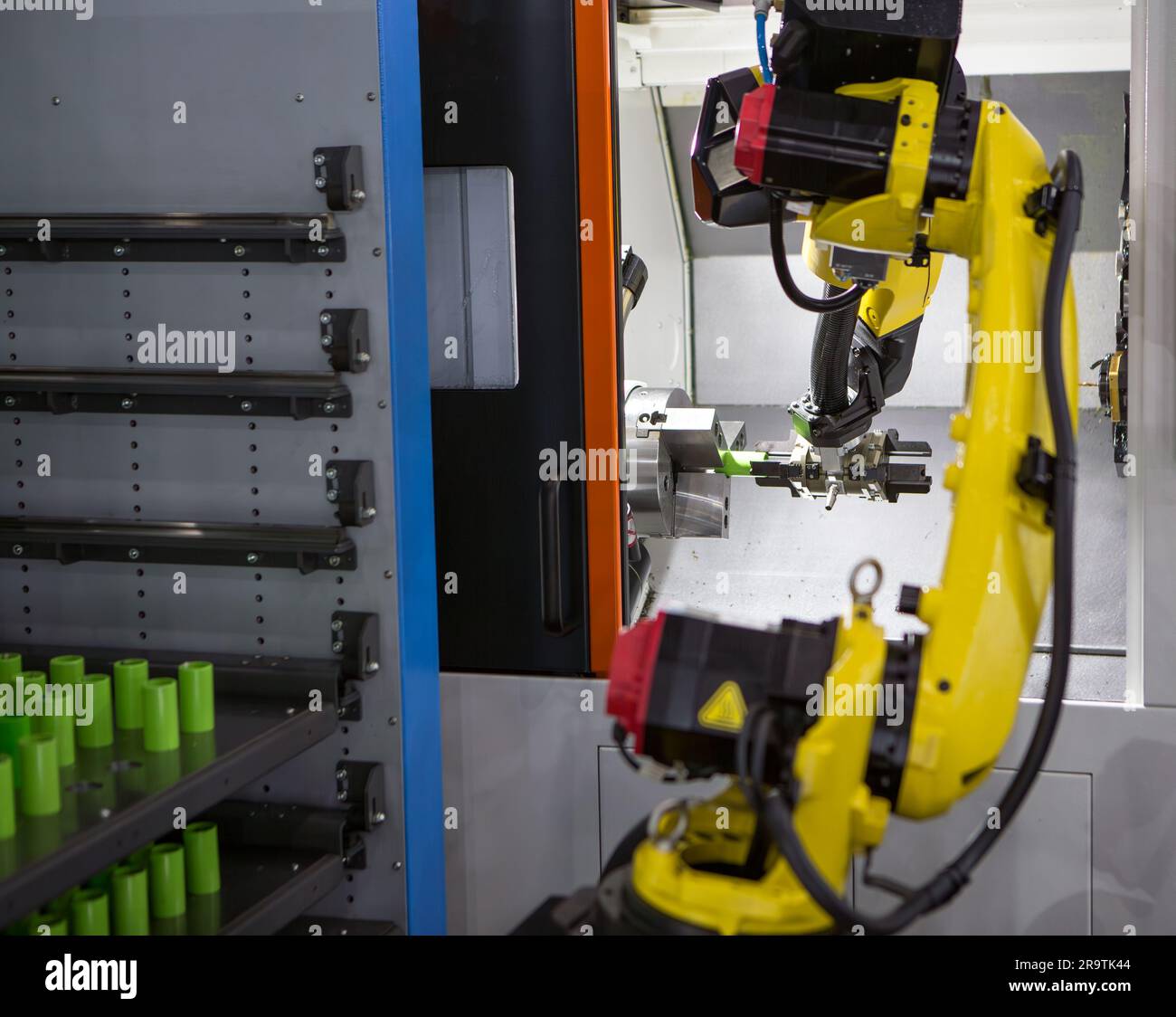 Automated manufacturing process. Robot arm loading workpieces on CNC ...