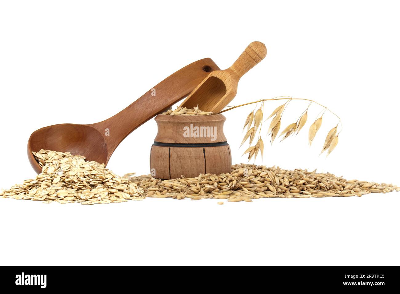 Oat groats rolled and flattened into flakes in wooden spoon and oat ...