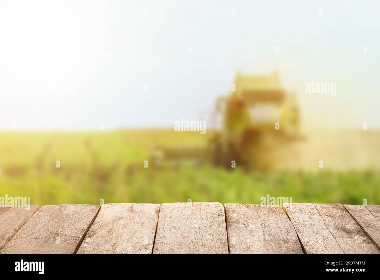 Empty wooden table in green field with combine harvester Stock Photo ...
