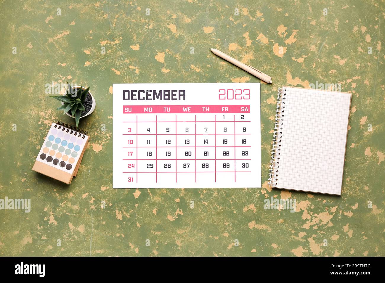Calendar, notebook, pen, houseplant and color palette on green table ...