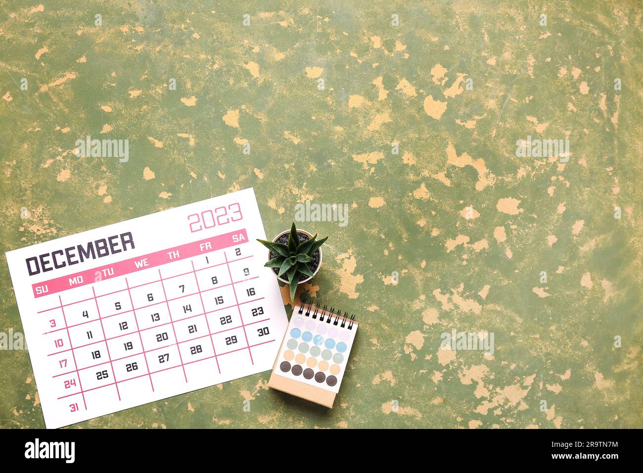 Calendar, houseplant and color palette on green table Stock Photo - Alamy