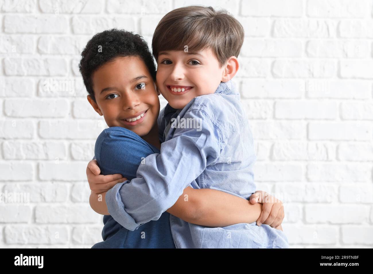 Cute little boys hugging near white brick wall, closeup Stock Photo - Alamy