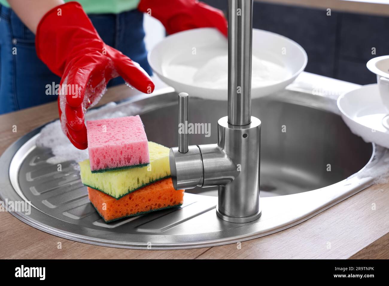 Woman in red rubber gloves washing dishes with sponge Stock Photo - Alamy
