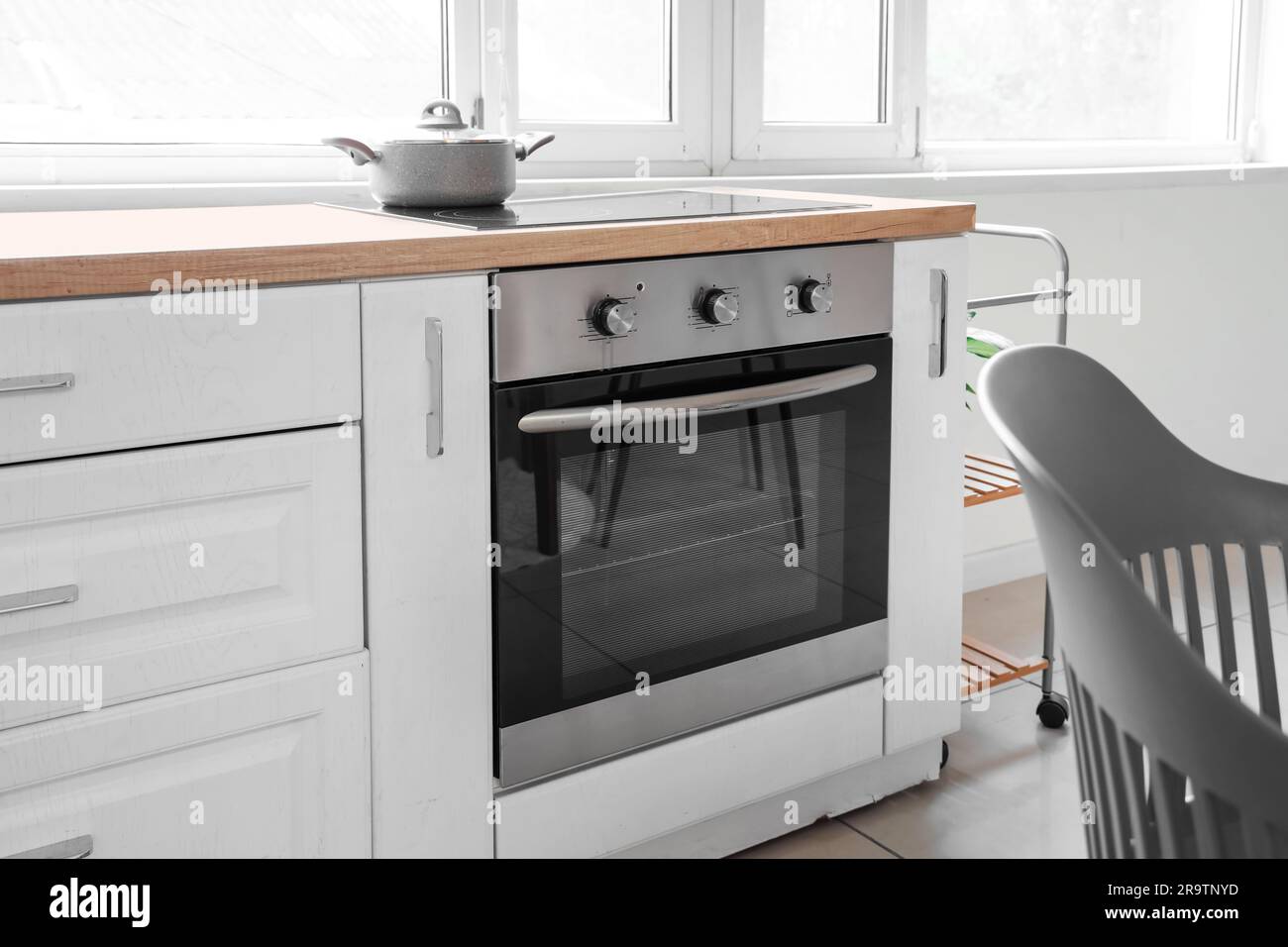 Electric oven with stove and cooking pot near window in modern kitchen ...