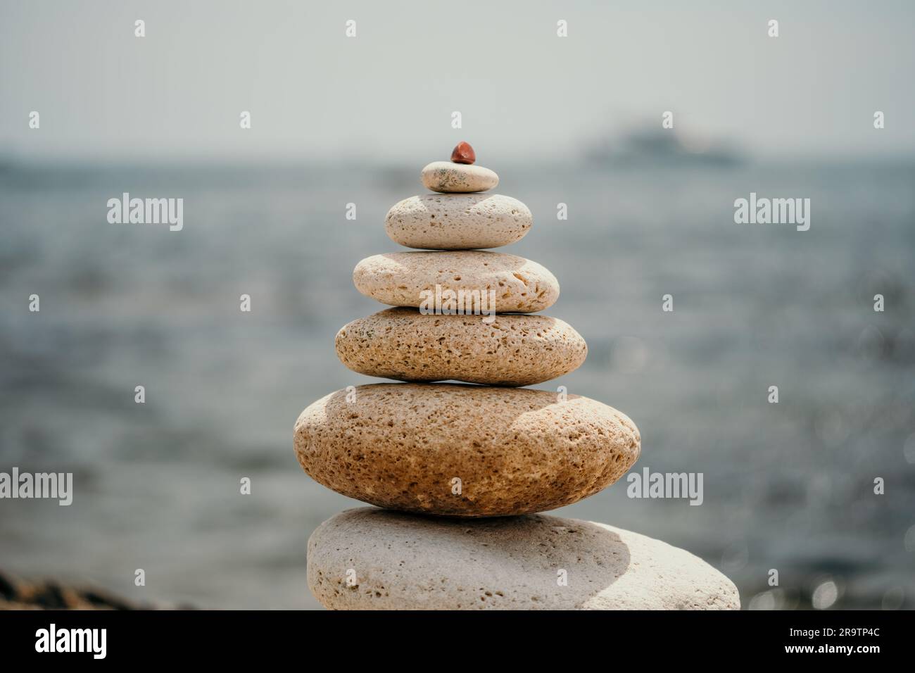 Zen stones and balanced rock pyramid on pebble beach at sunset. Golden ...