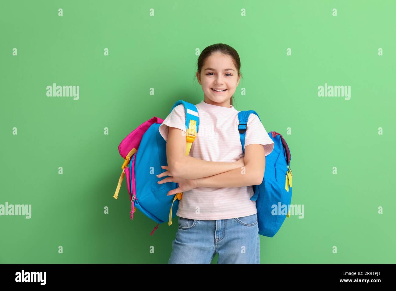 Little girl with backpacks on green background Stock Photo - Alamy