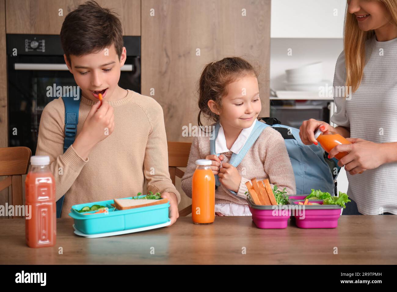 Little children with school lunch and their mother in kitchen Stock ...