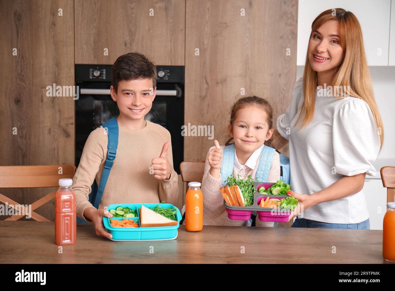 Little children with school lunch and their mother in kitchen Stock ...
