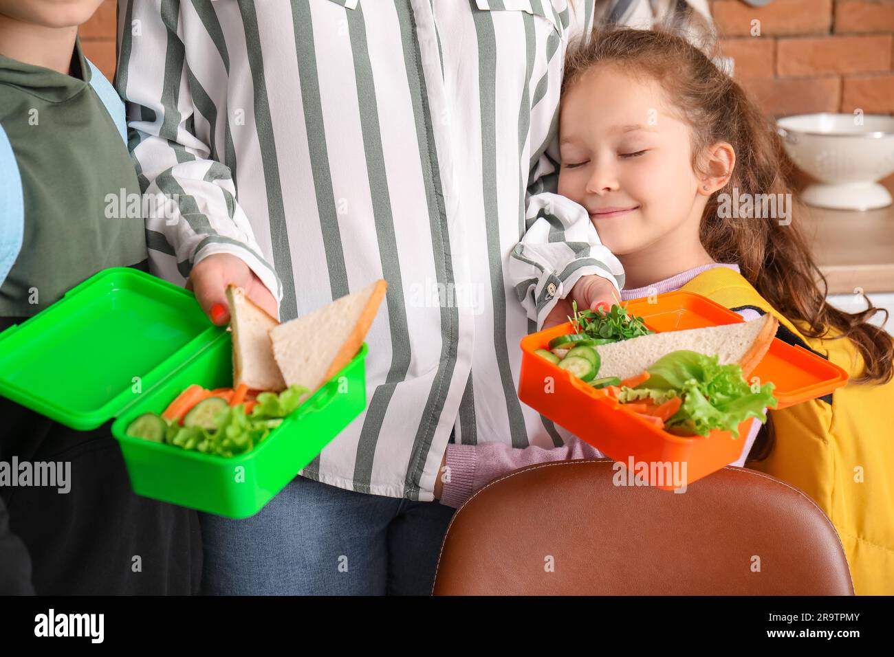 Little children with school lunch and their mother in kitchen, closeup ...