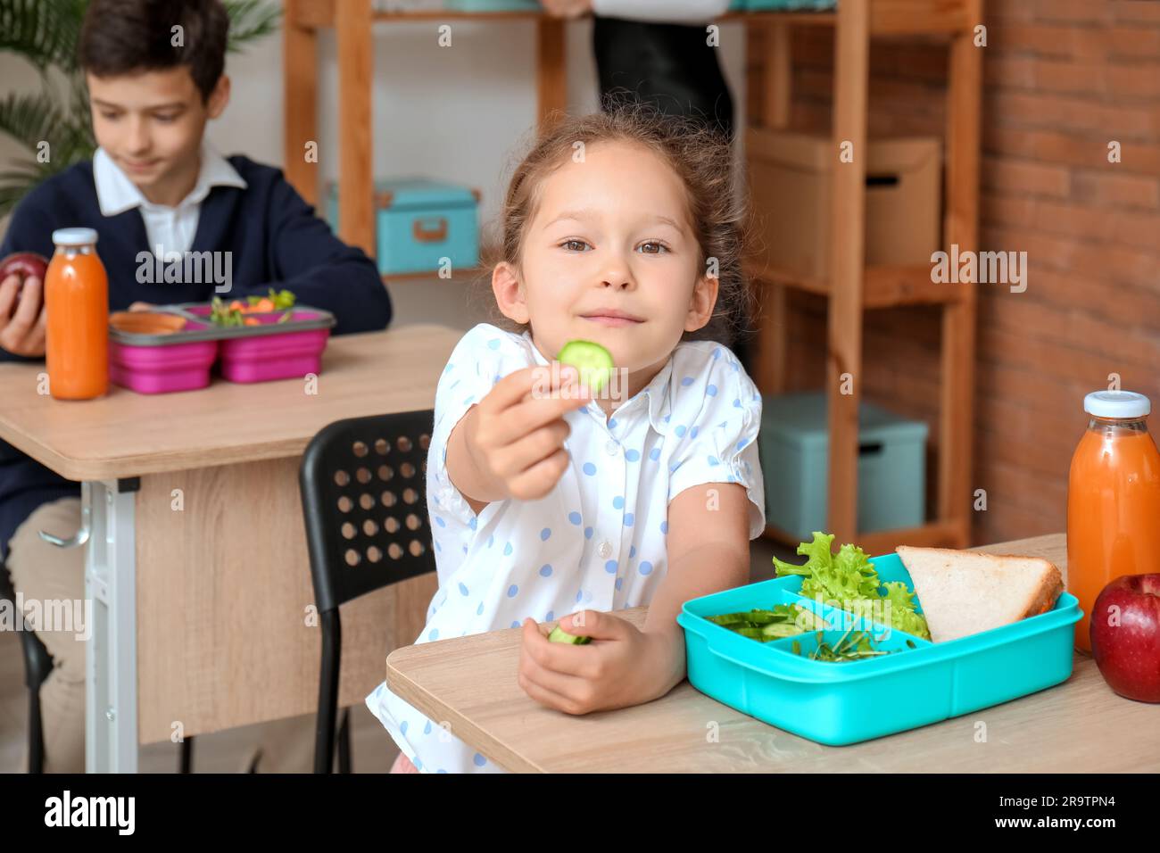 Little girl eating lunch in classroom Stock Photo - Alamy