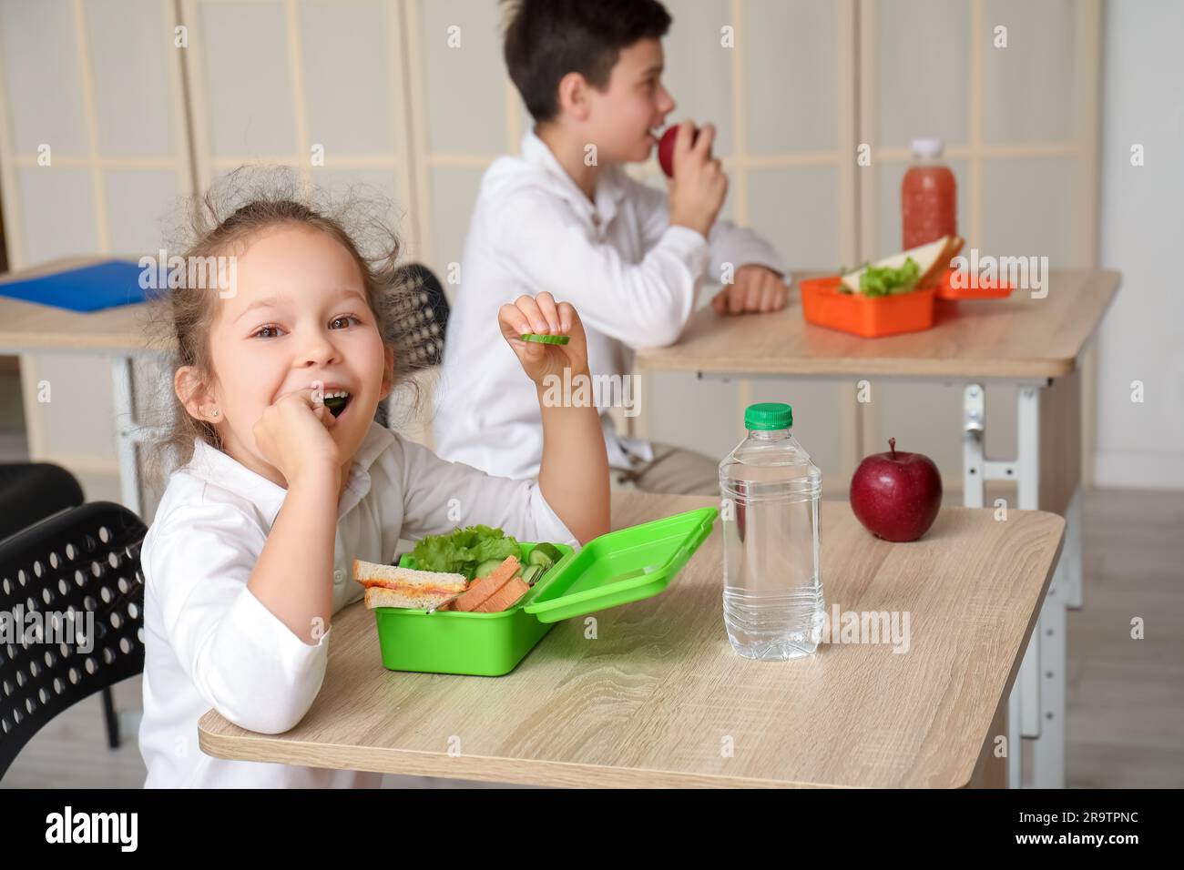 Little girl eating lunch in classroom Stock Photo - Alamy