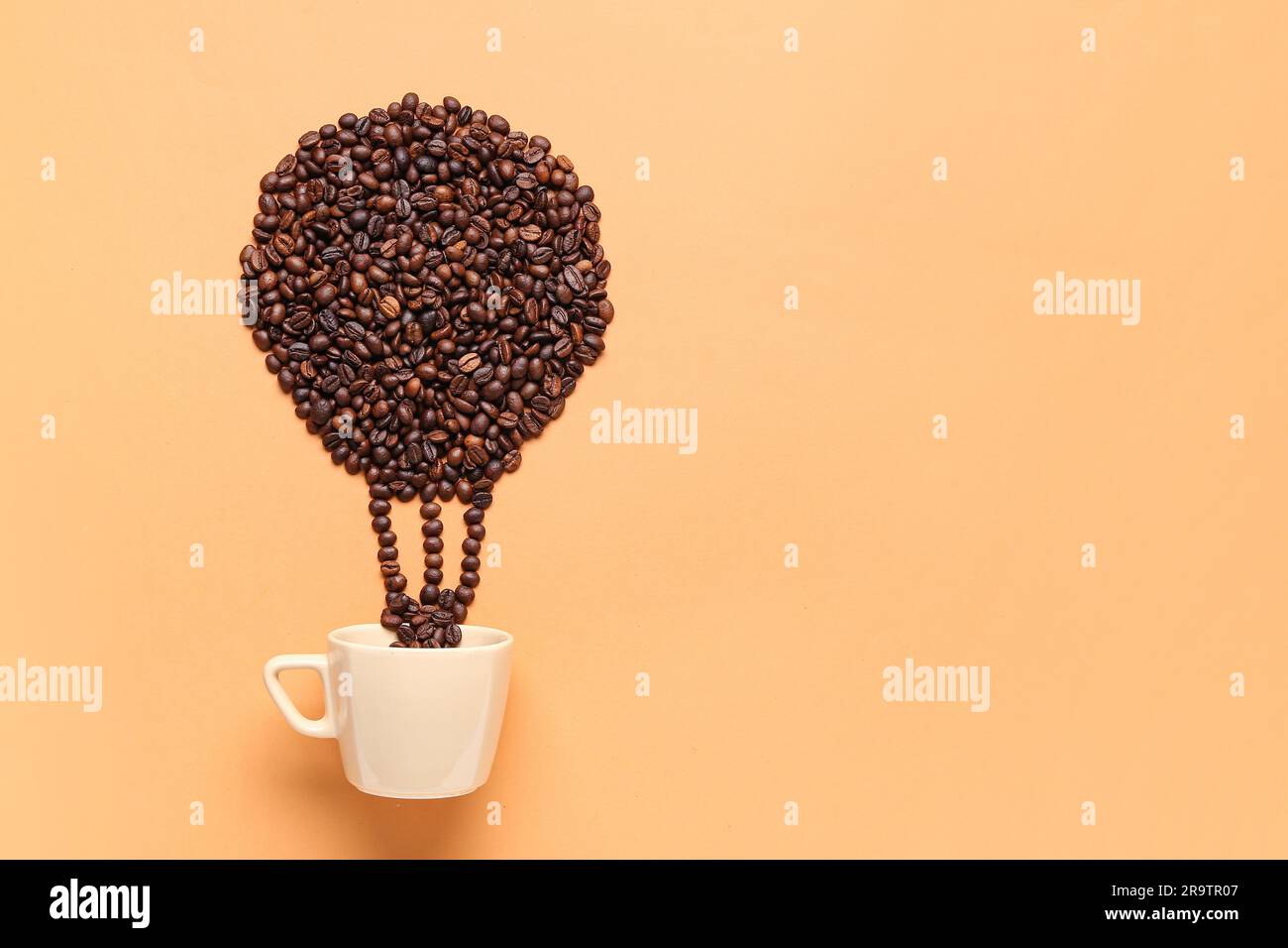Coffee beans spilled from cup in shape of air balloon on orange ...