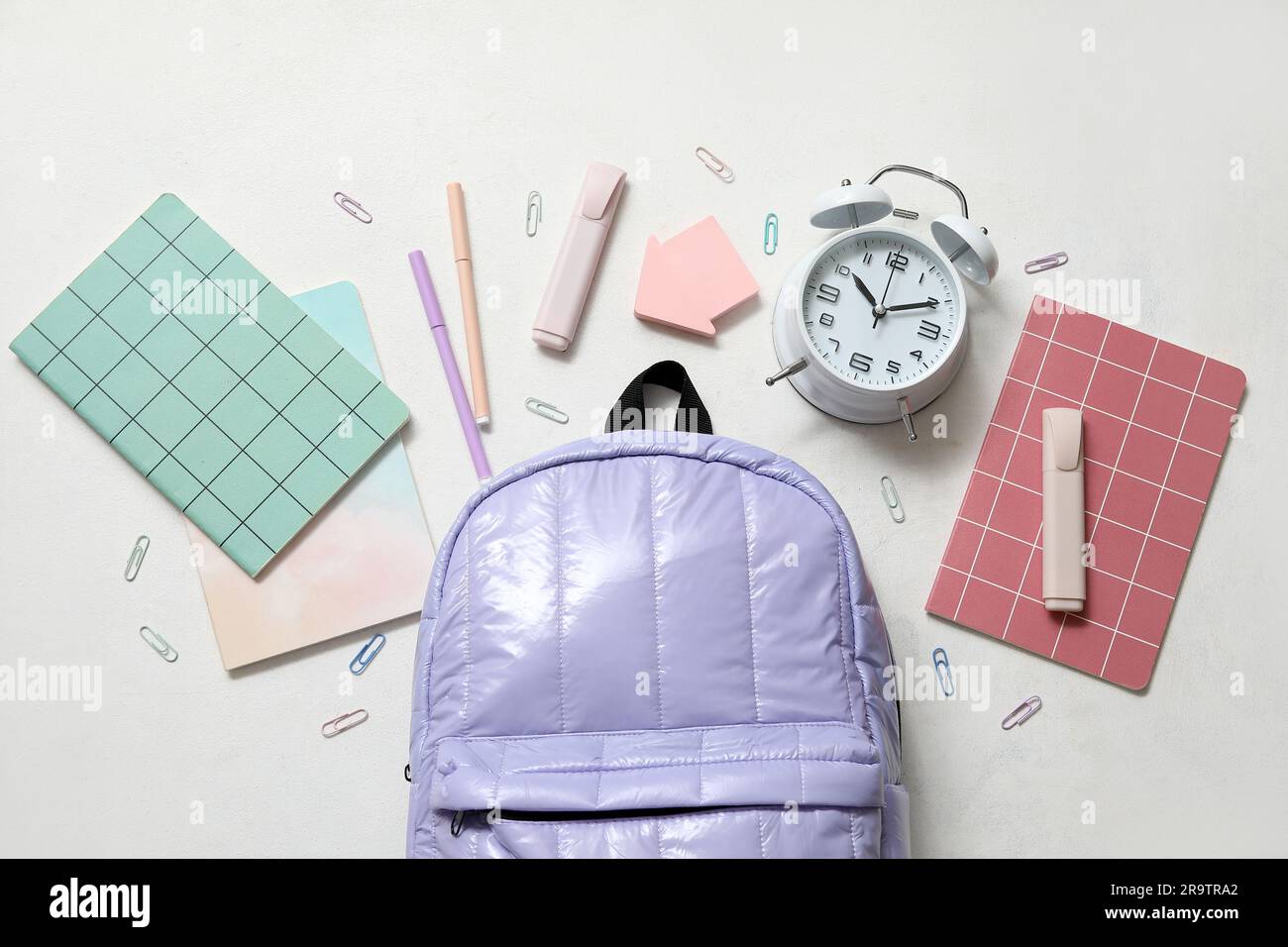 Lilac school backpack with notebooks, alarm clock and markers on white ...