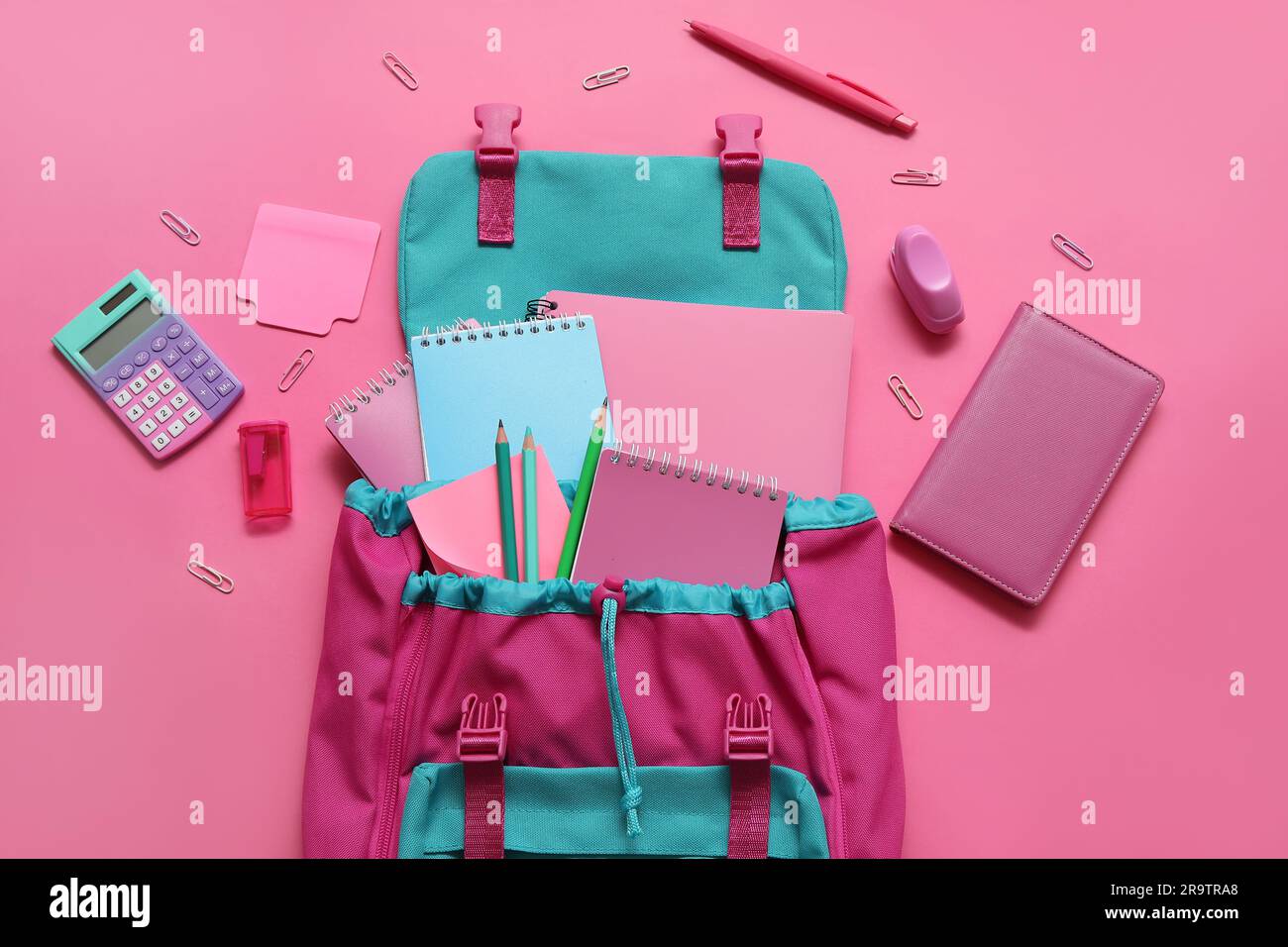 Colorful school backpack with notebooks, calculator and pencils on pink ...
