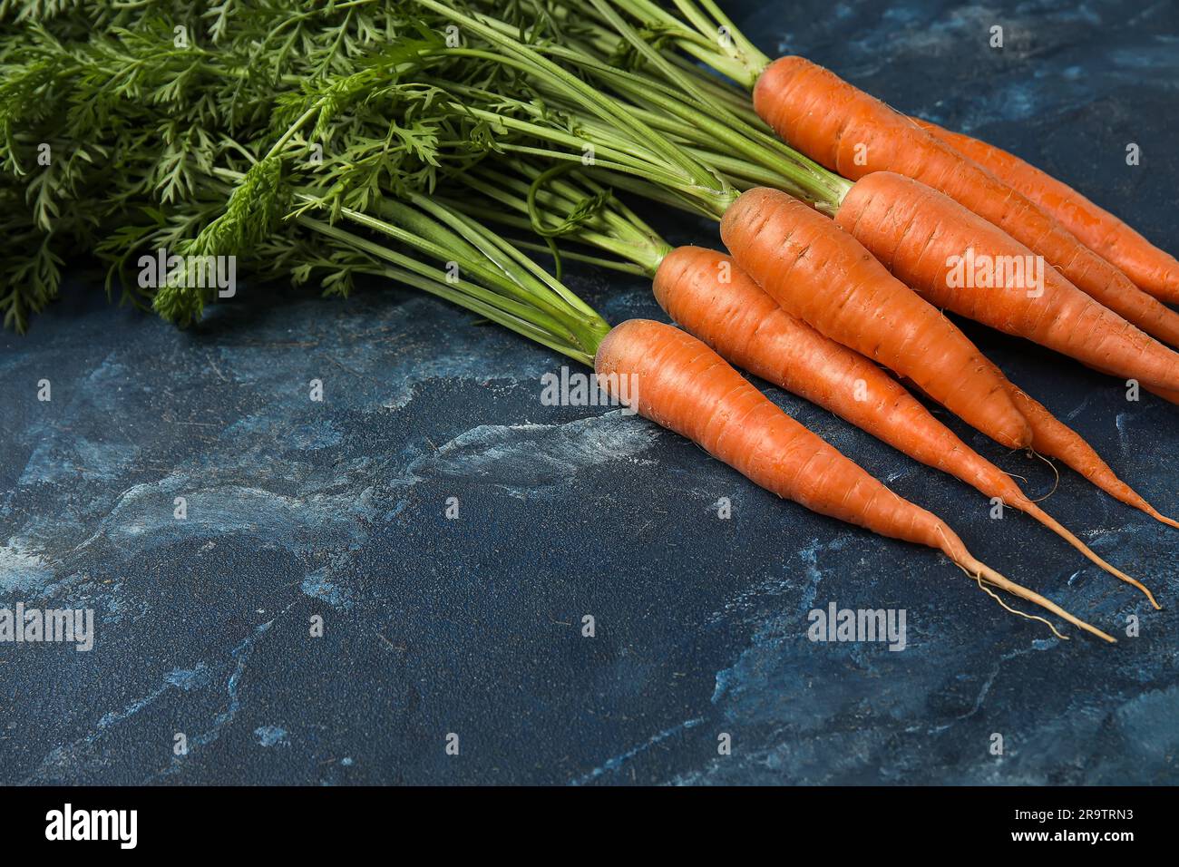 Fresh carrots with leaves on blue background Stock Photo - Alamy