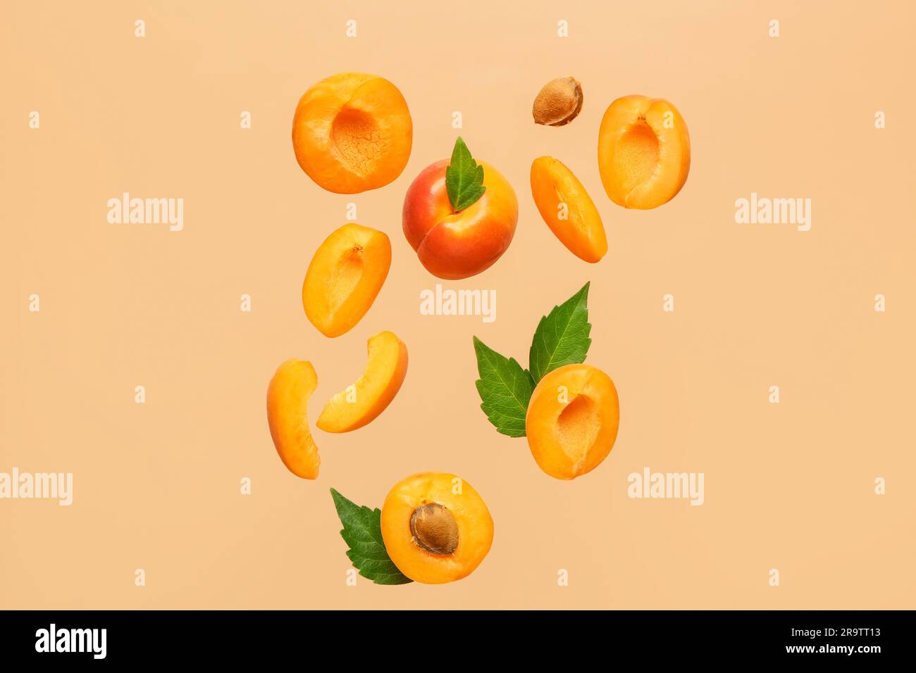 Flying fresh apricot with pieces and leaves on orange background Stock ...