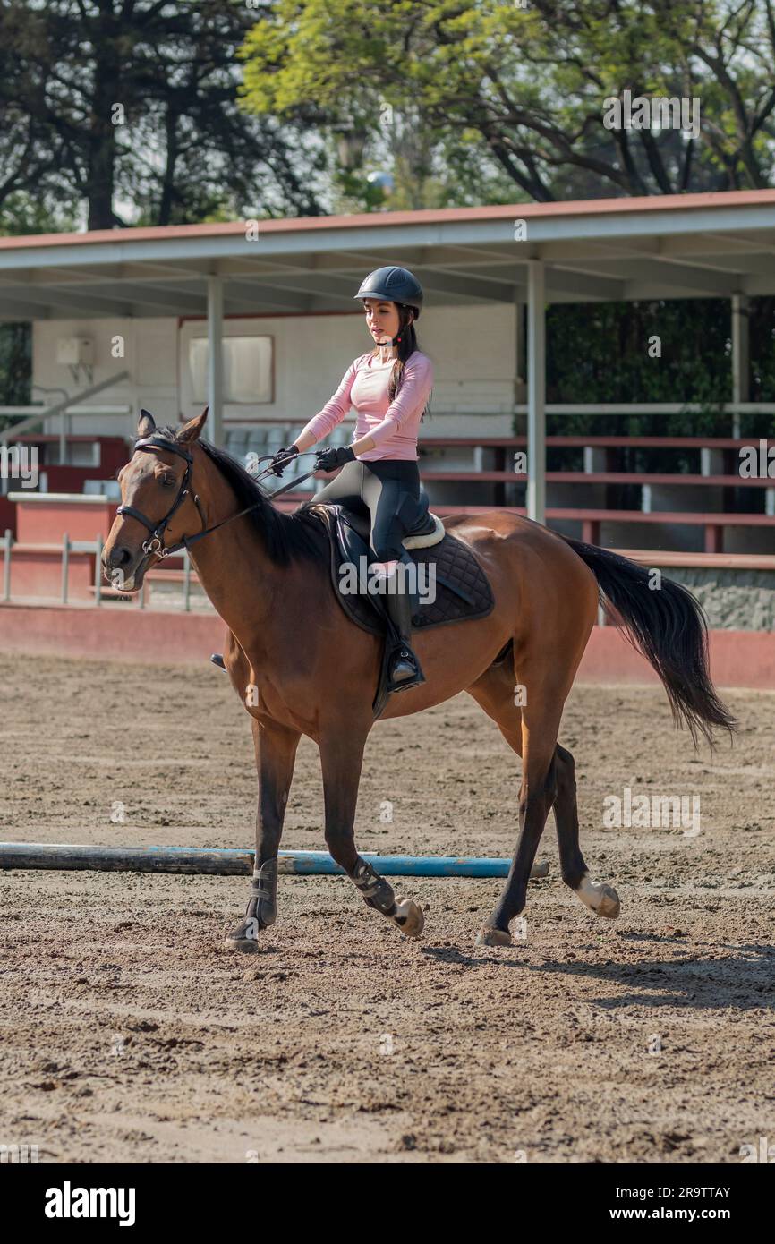 Vertical image of a young woman who is riding a horse while taking ...